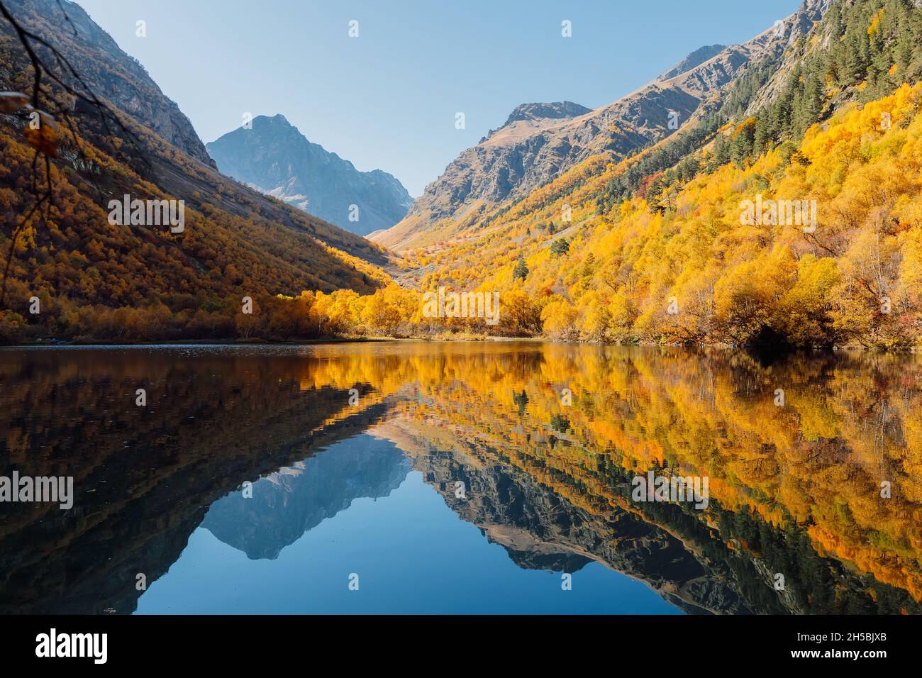 Lake with transparent water and yellow autumnal trees. Mountains and ...