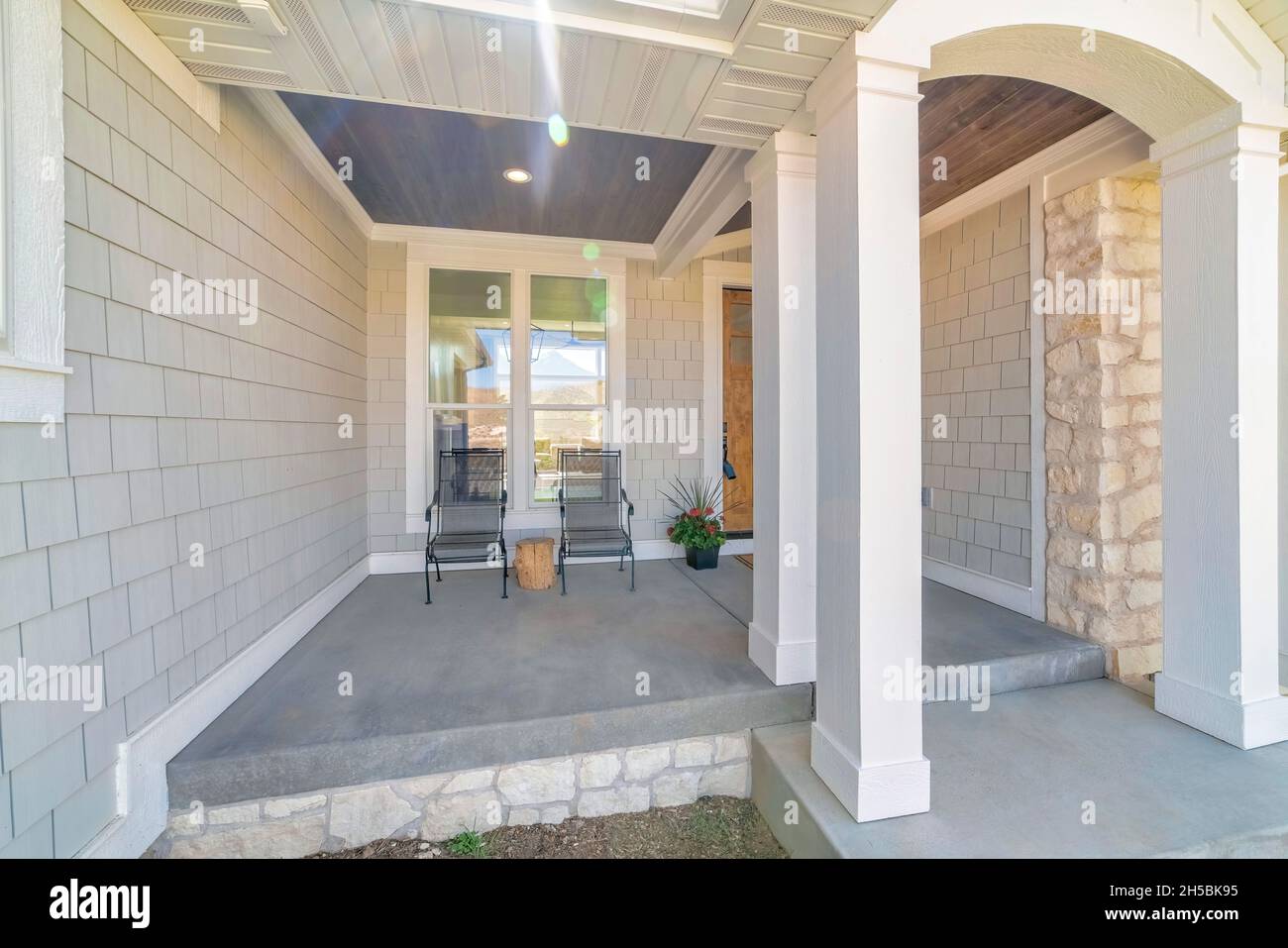 Entrance of a house with porch arched columns and beige shingles siding ...