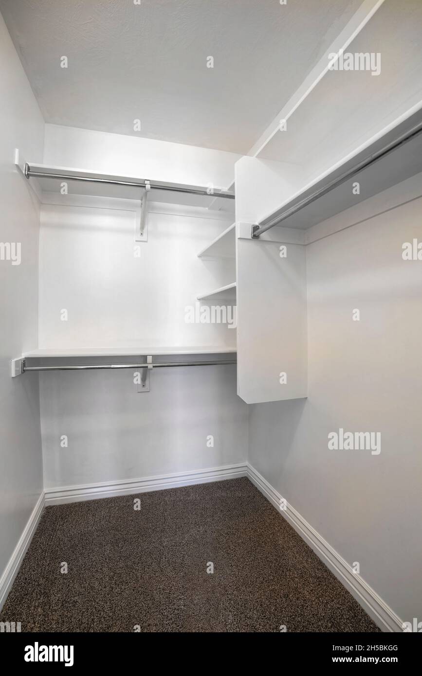 Small walk in closet with metal rods and white shelving unit Stock ...