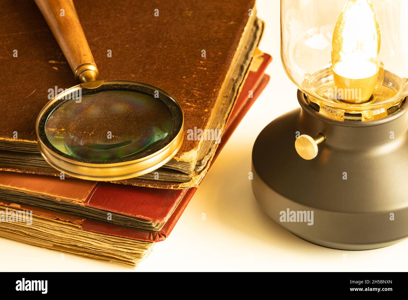 Old albums lying on the desk with a magnifying glass and a stylish lamp ...