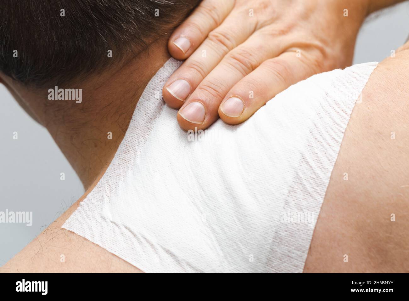 Warming patch glued to the neck, The man is holding on to the sore ...