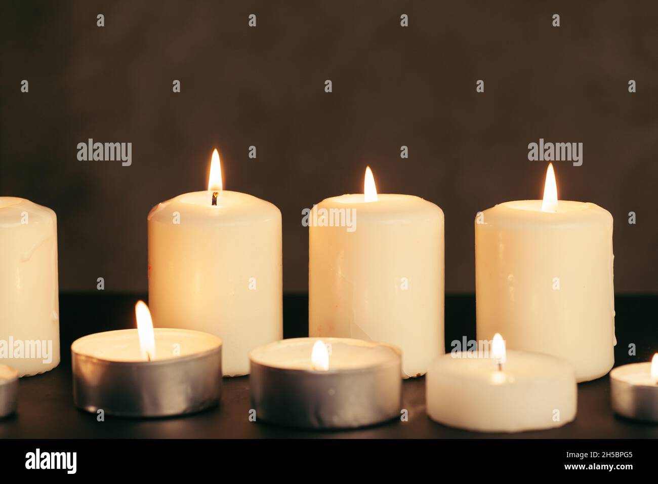 Many candles burning at night. Many candle flames glowing on dark ...