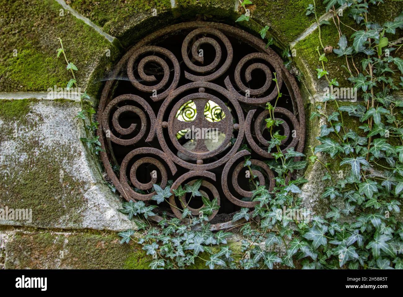 A Round window with bars in a historic stone tomb Stock Photo - Alamy