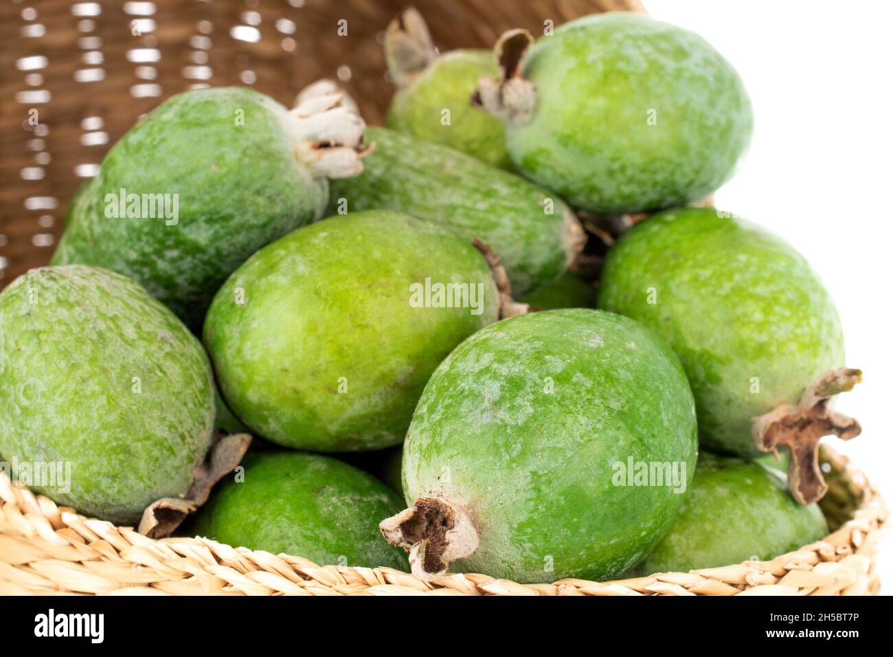 Several organic sweet feijoa fruits with straw dishes, close-up ...