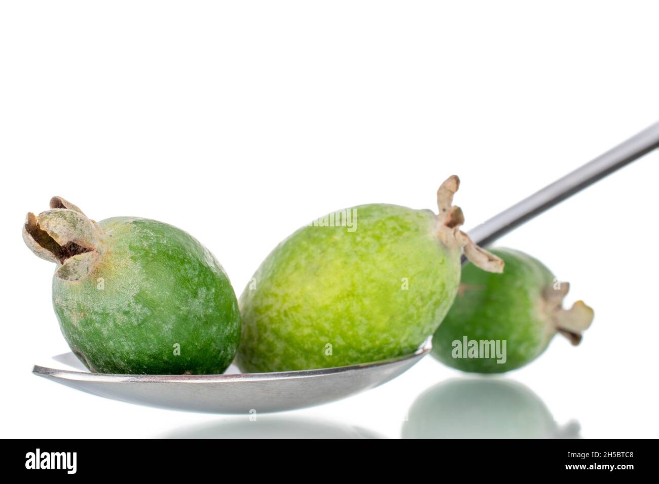 Three ripe sweet fruits of feijoa with a metal spoon, close-up ...