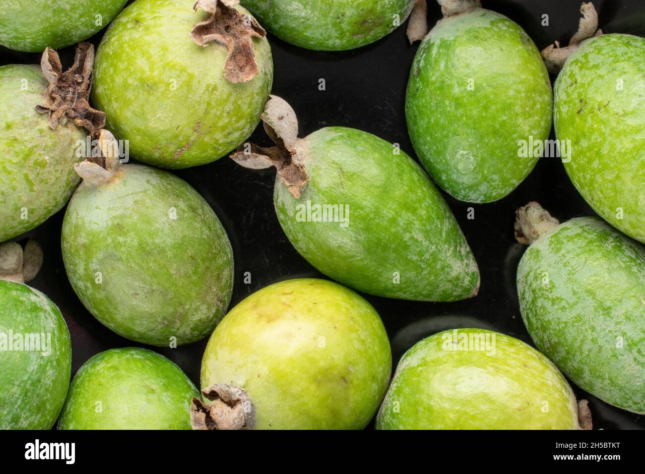 Several fragrant sweet feijoa fruits in a black bowl, close-up, top ...