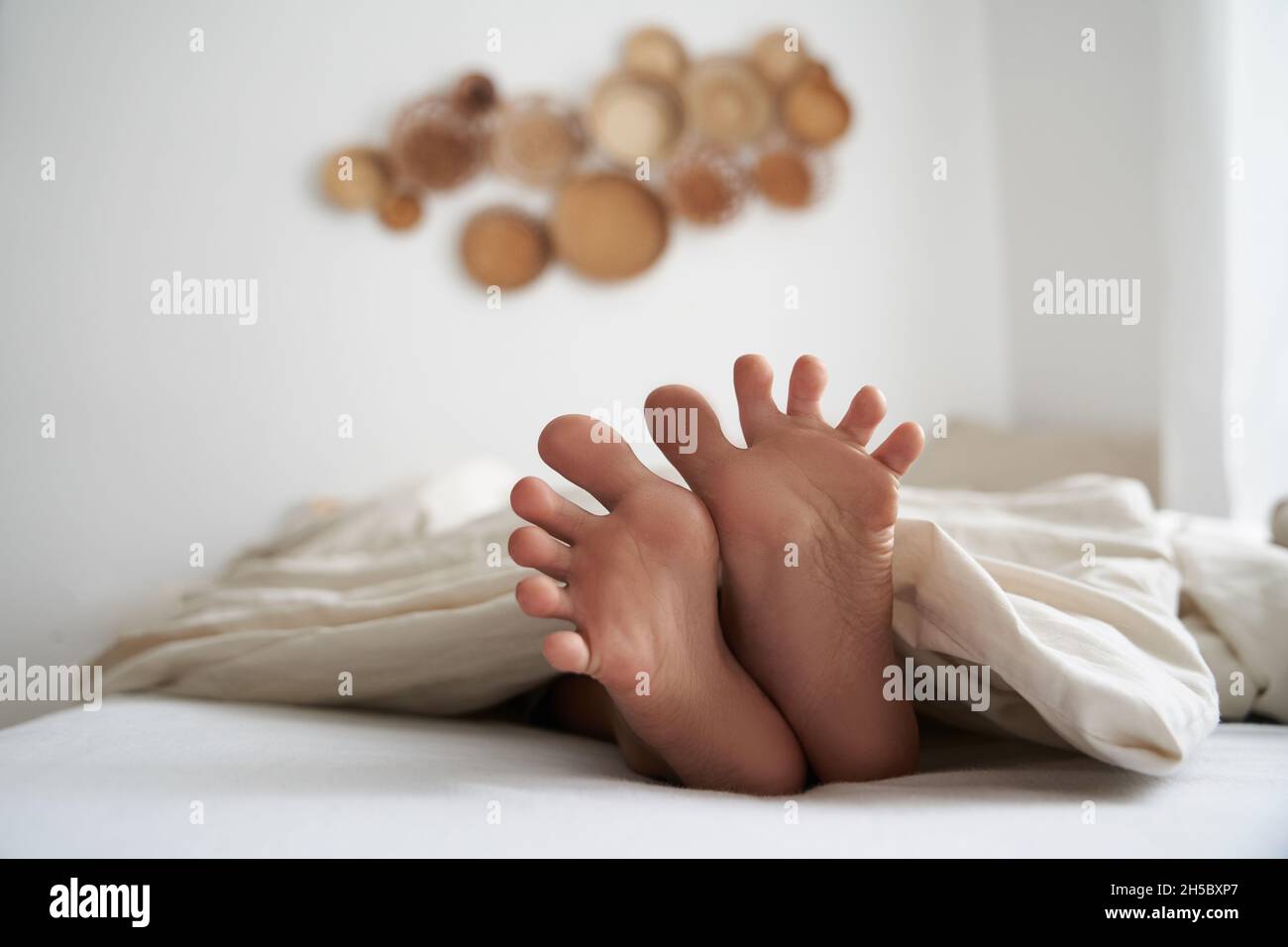 Close-up of a child's feet lying in bed in the morning, in the sunlight ...