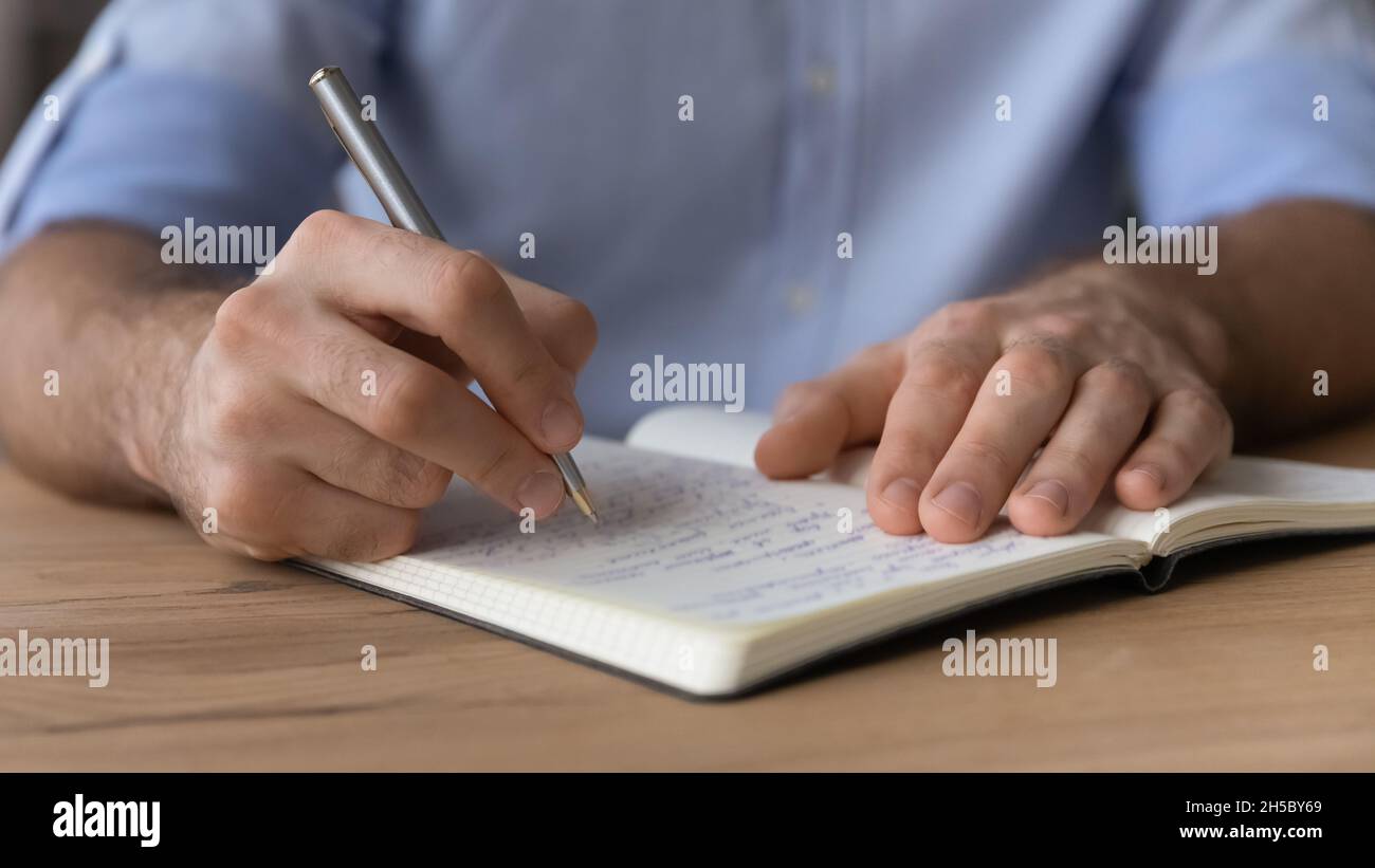 Young man handwriting notes in paper planner Stock Photo - Alamy