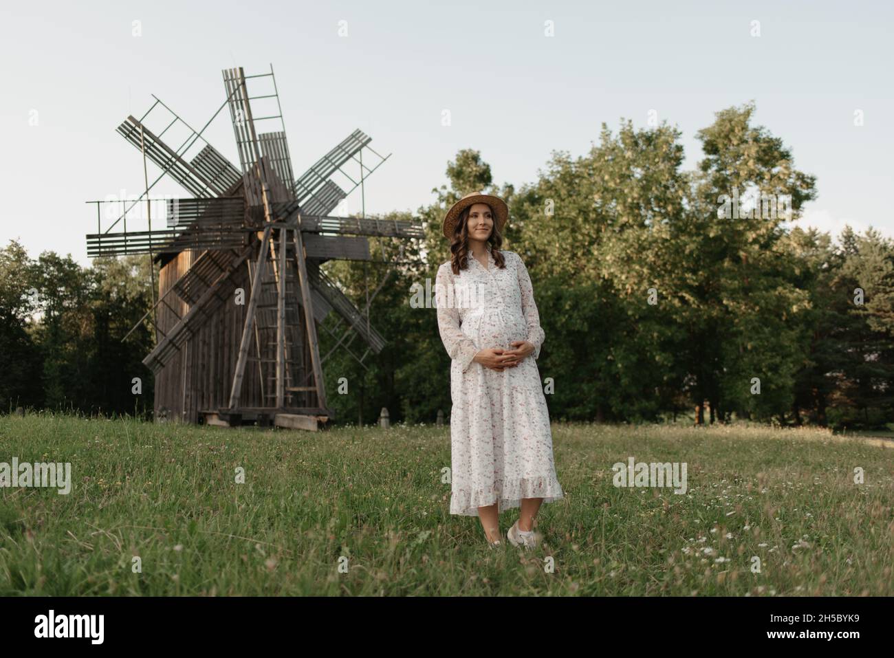 A full-length portrait of a pregnant woman in the windmill background ...