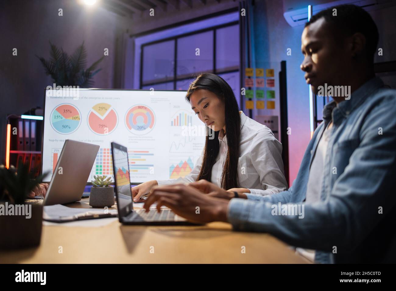 African american man and asian woman typing on modern laptop and ...