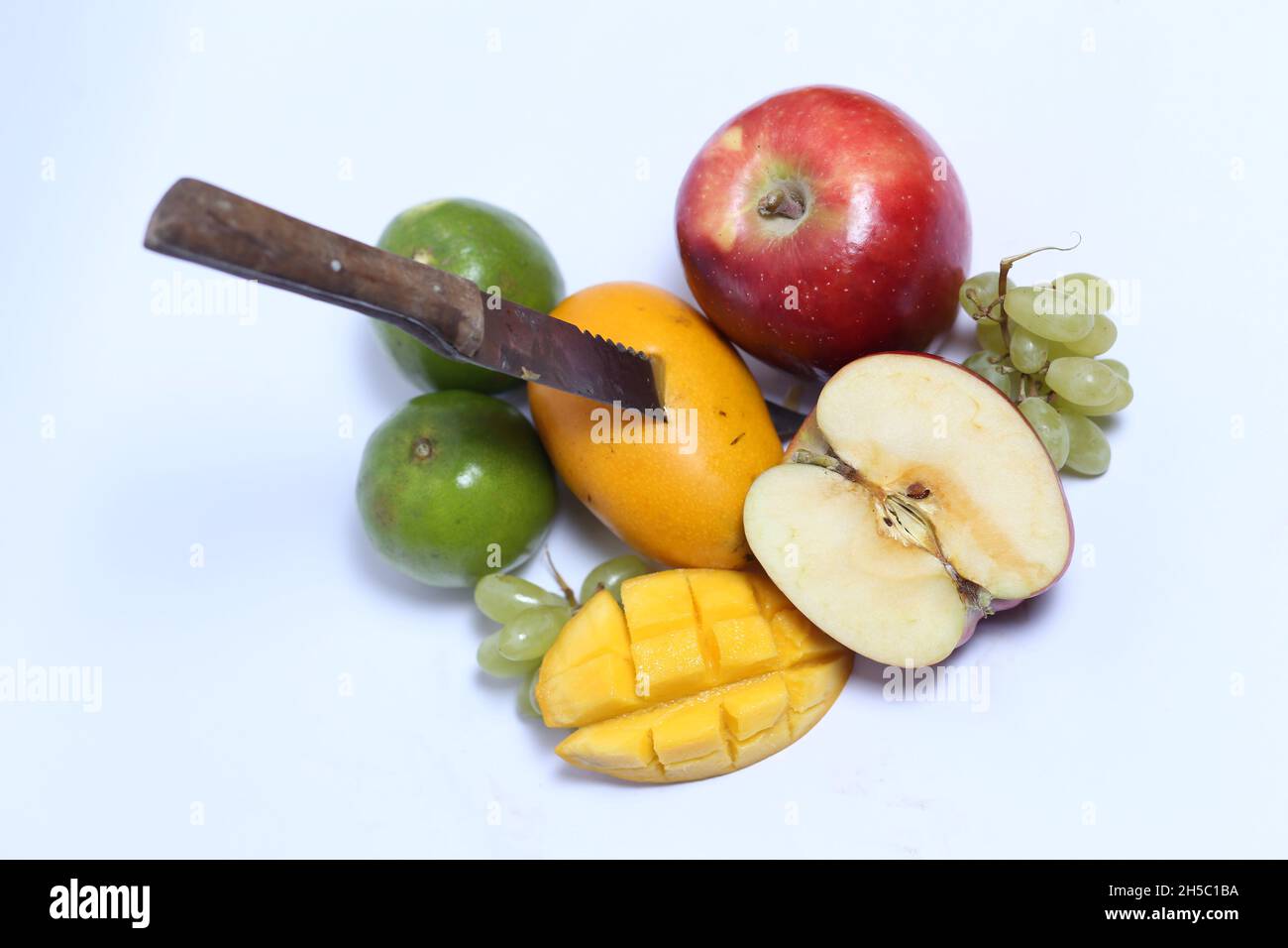 Apple, mango, grapes, Citrus limetta and a knife isolated on white ...