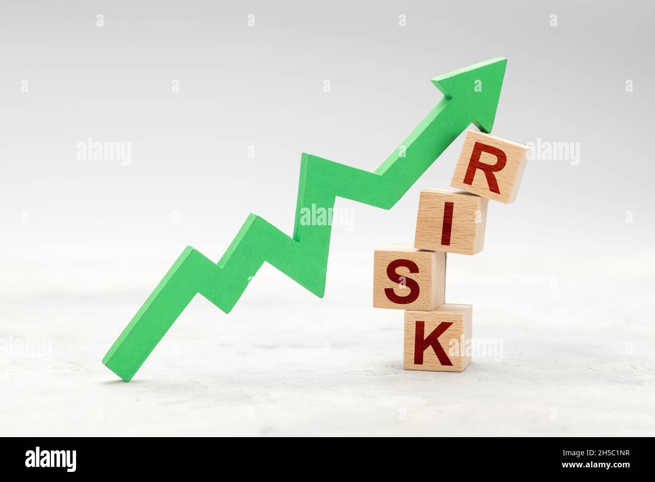 High risk. Green up arrow and RISK cubes on gray background Stock Photo ...