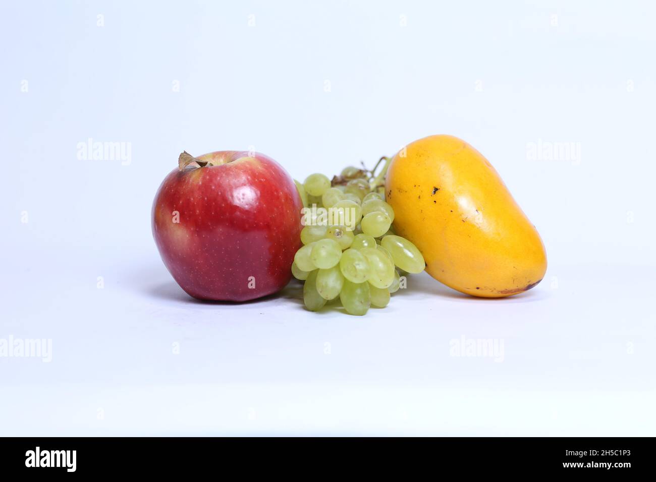 Mango, an apple and grapes isolated on white background Stock Photo - Alamy