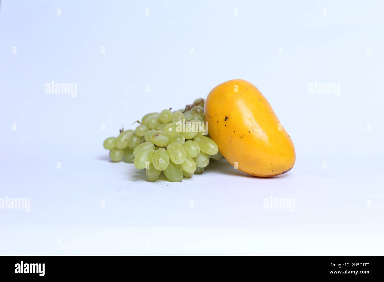 Grapes and a mango isolated on white background Stock Photo - Alamy