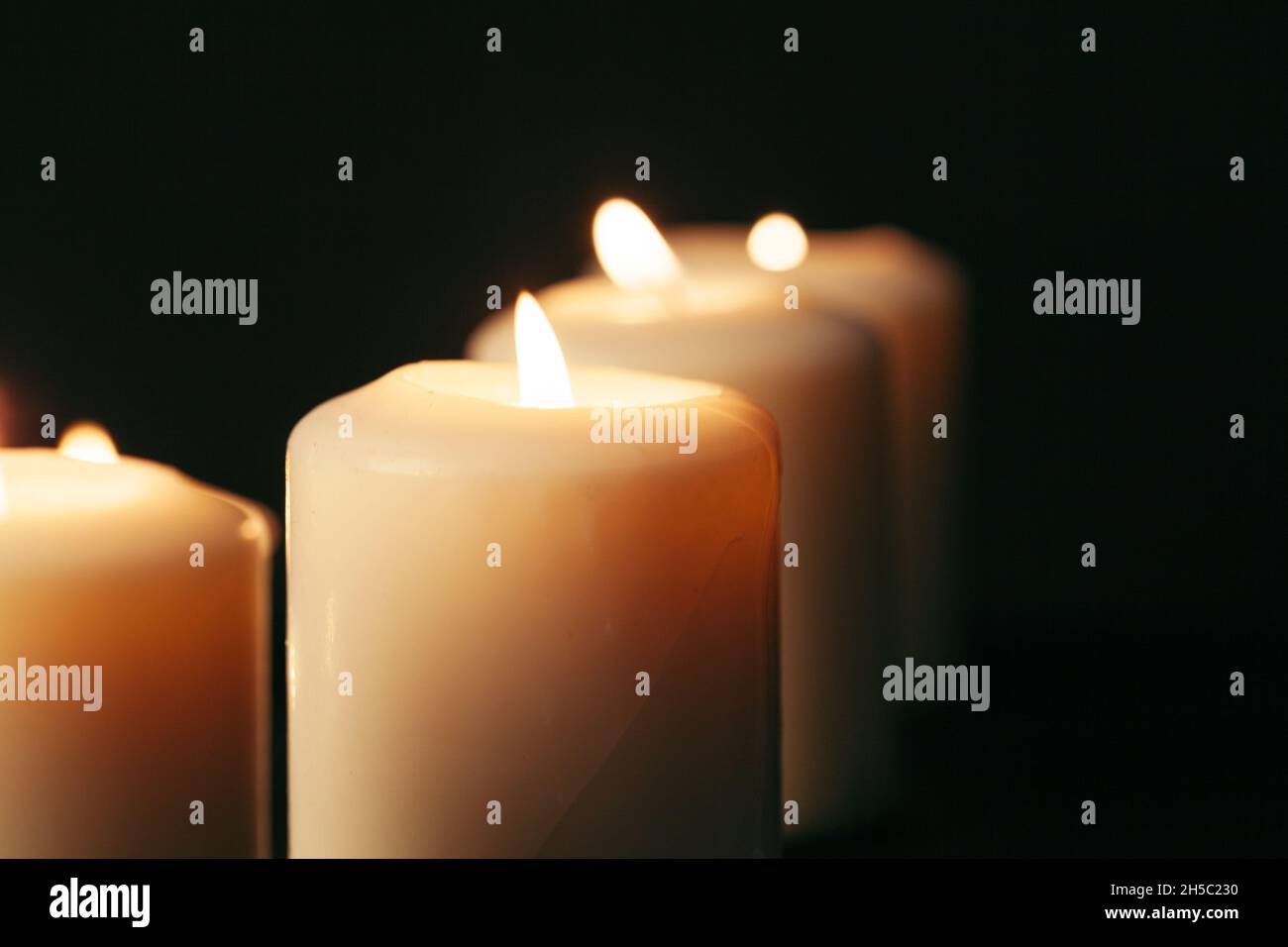 Many candles burning at night. Many candle flames glowing on dark ...