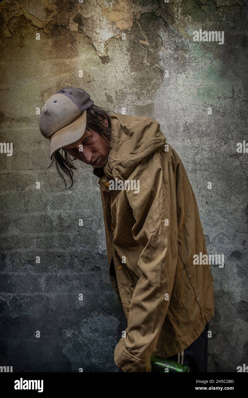 Junkie man with cap green anorak and blue sweatpants near stone old ...