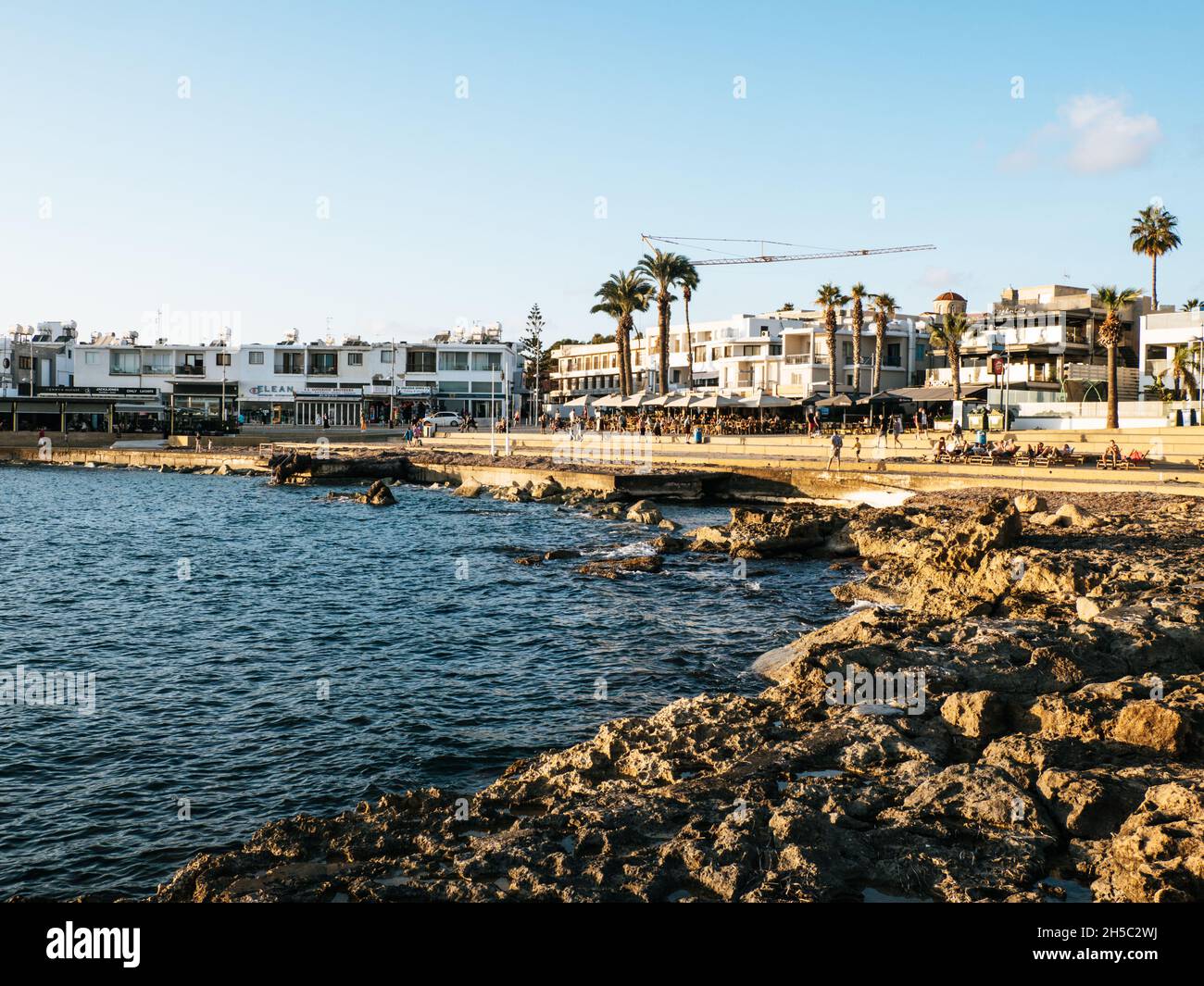 View of Paphos harbour and its rocky shore at sunset on the island ...