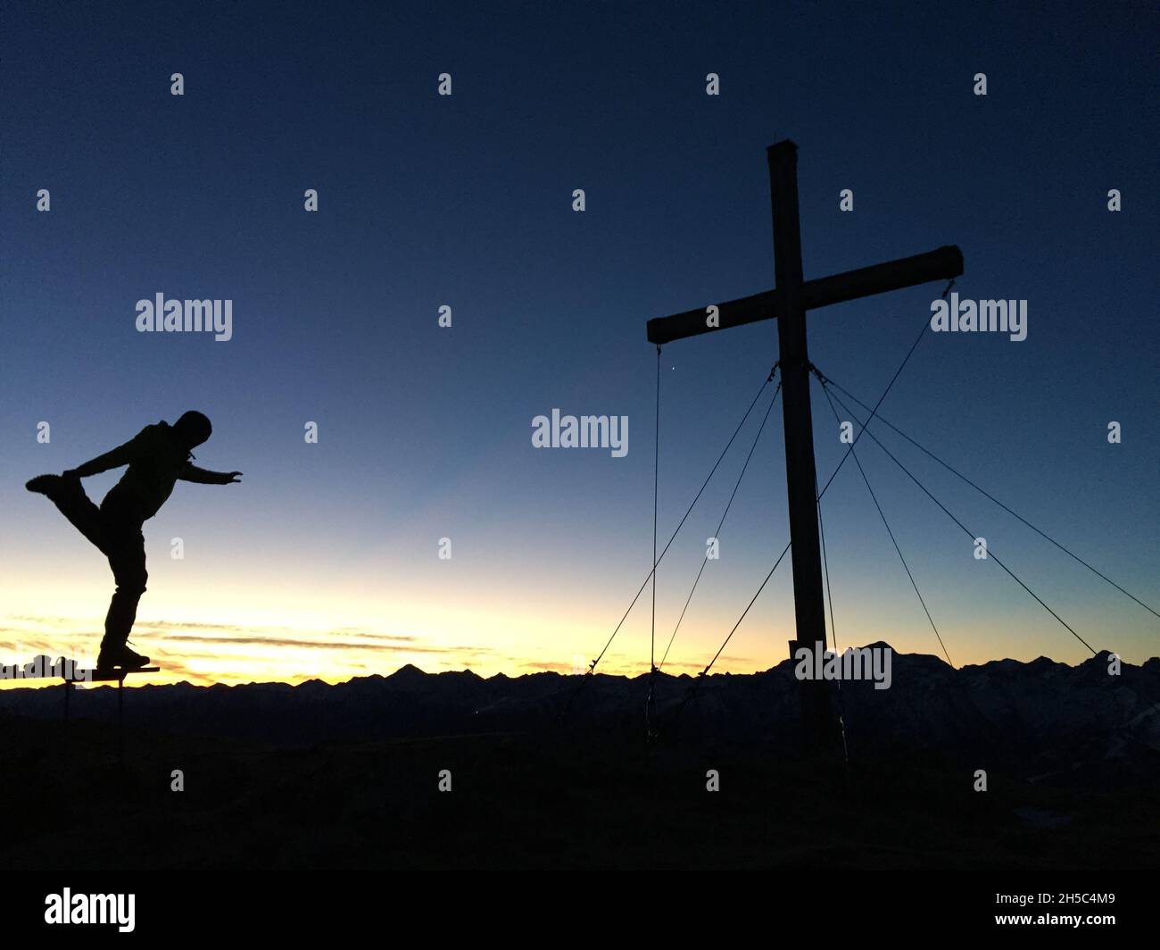 Inverted silhouette of a human doing tricks next to a cross during ...