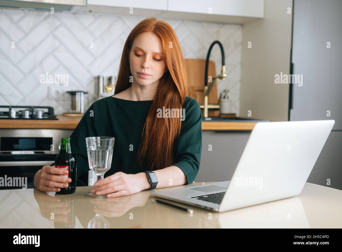 Attractive young woman pouring alcohol beverage in glass sitting at ...