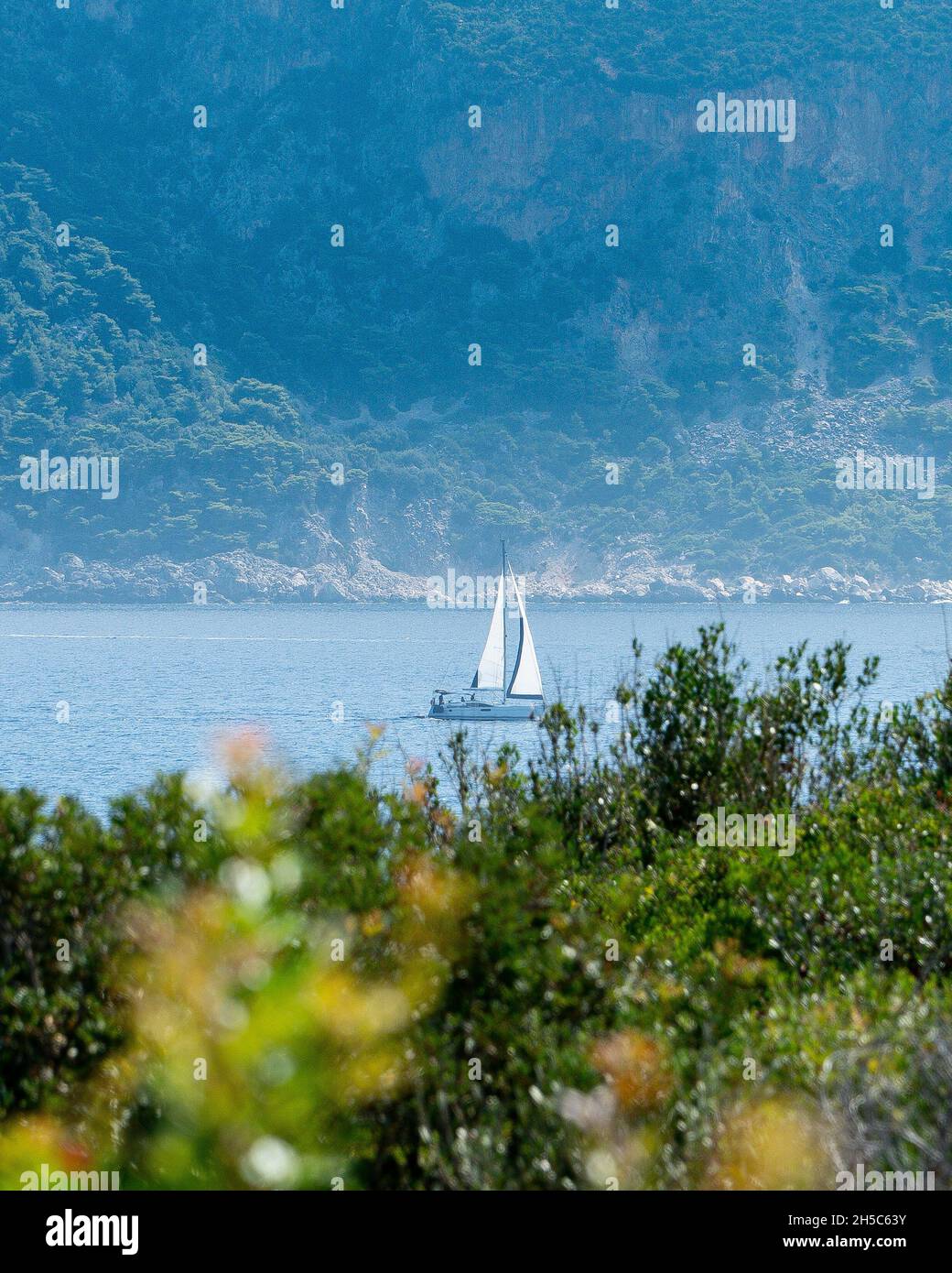 Vertical shot of a small sail ship in a lake with a background of high ...