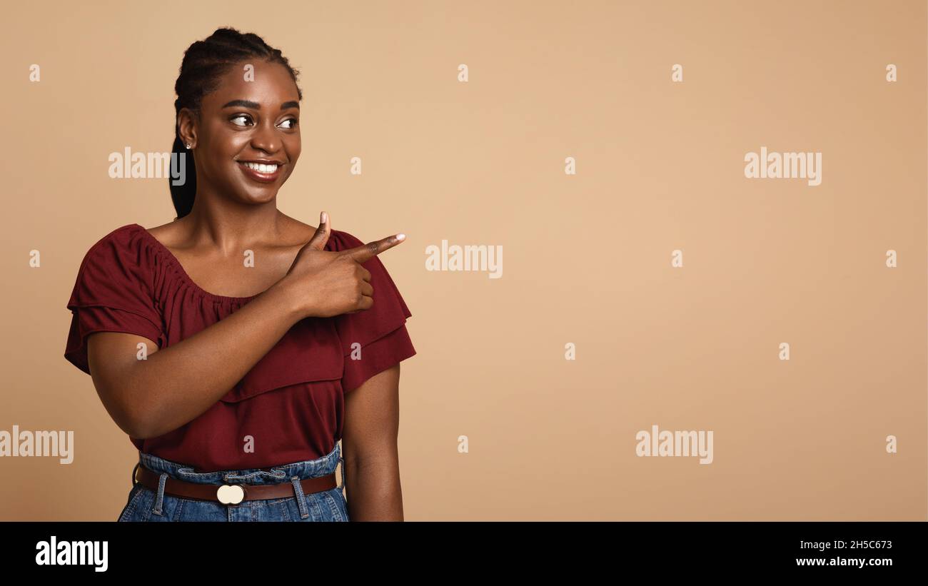 Attractive african american woman showing advertisement on beige Stock ...