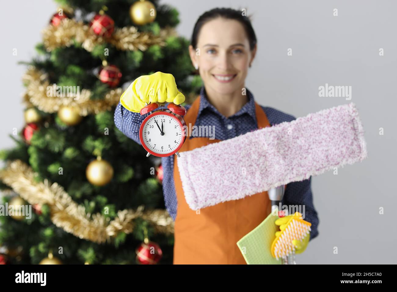 Employee of cleaning company holds mop and alarm clock against ...