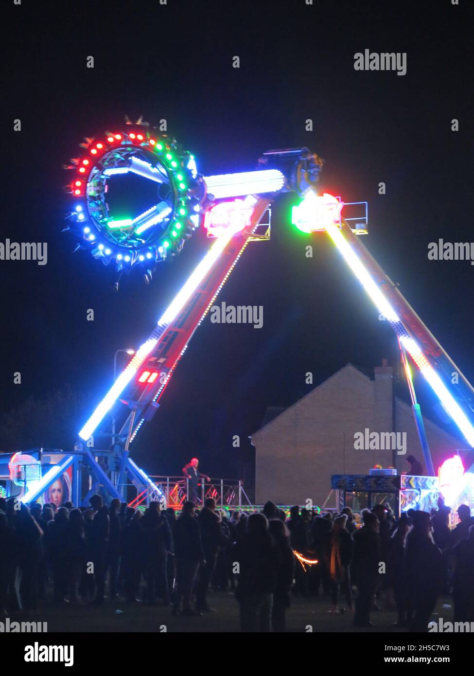 Funfair at night: bright red, blue & green lights on the swinging arm ...