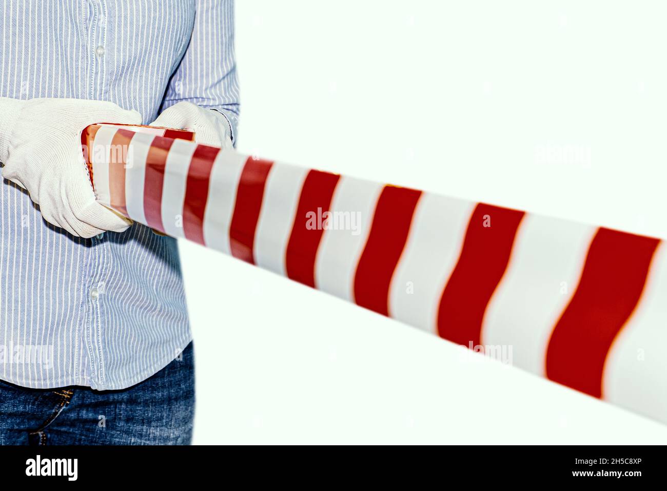 A young woman pulls a red and white restrictive tape. The concept of ...
