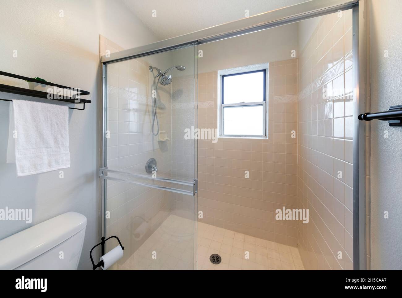 Shower stall inside a bathroom with beige square tiles and sliding ...