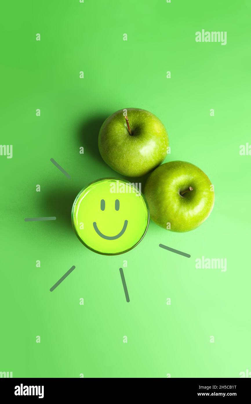 With a smile drawn on an apple juice with two apples on a green ...