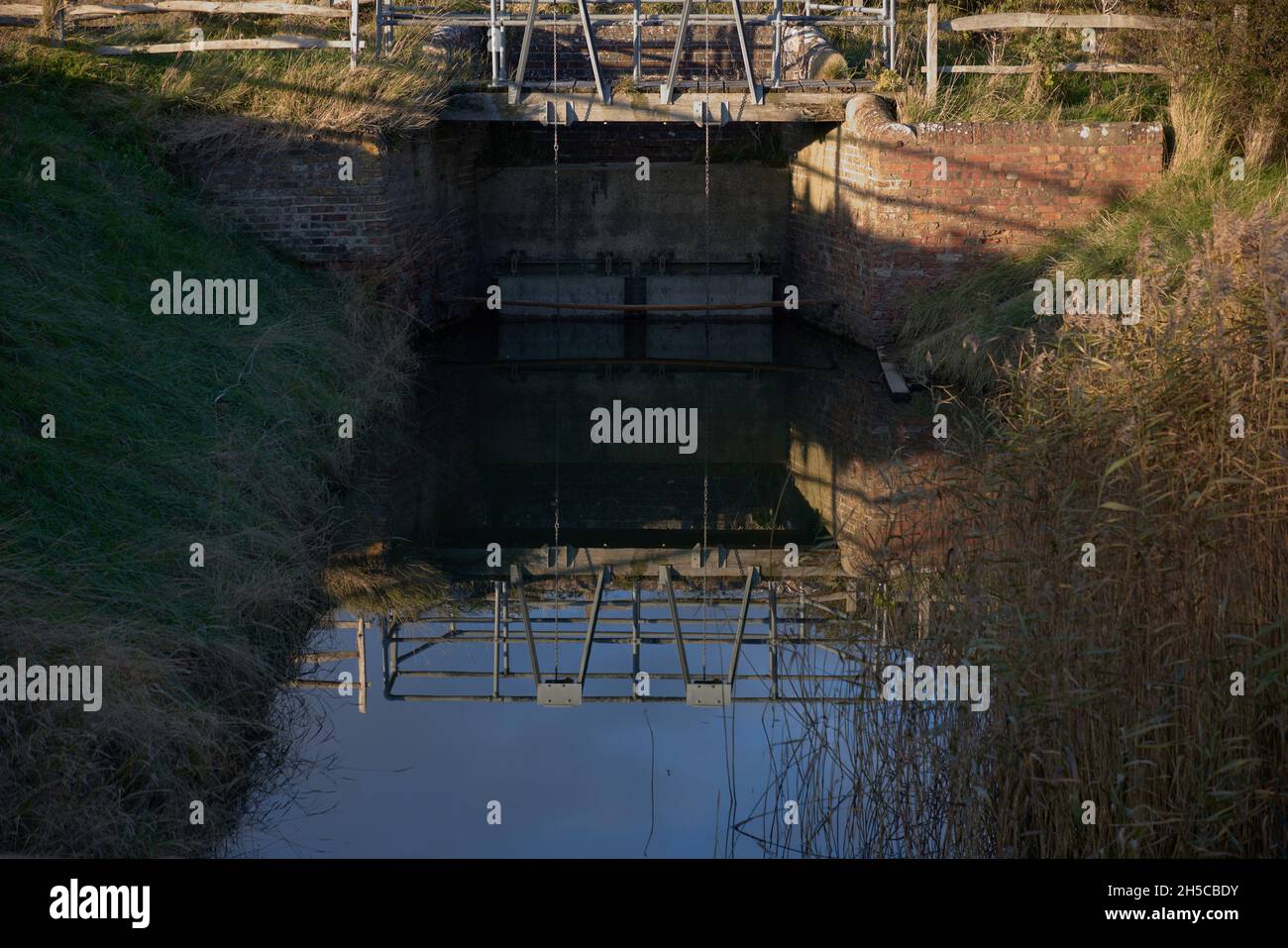 Sluice construction with water channel and sloping grass bank Stock ...