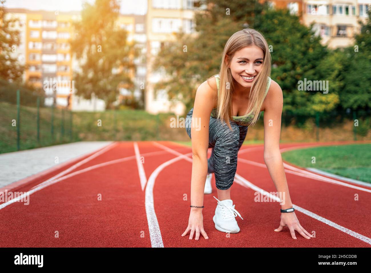 Positive girl at low start getting ready to run Stock Photo - Alamy