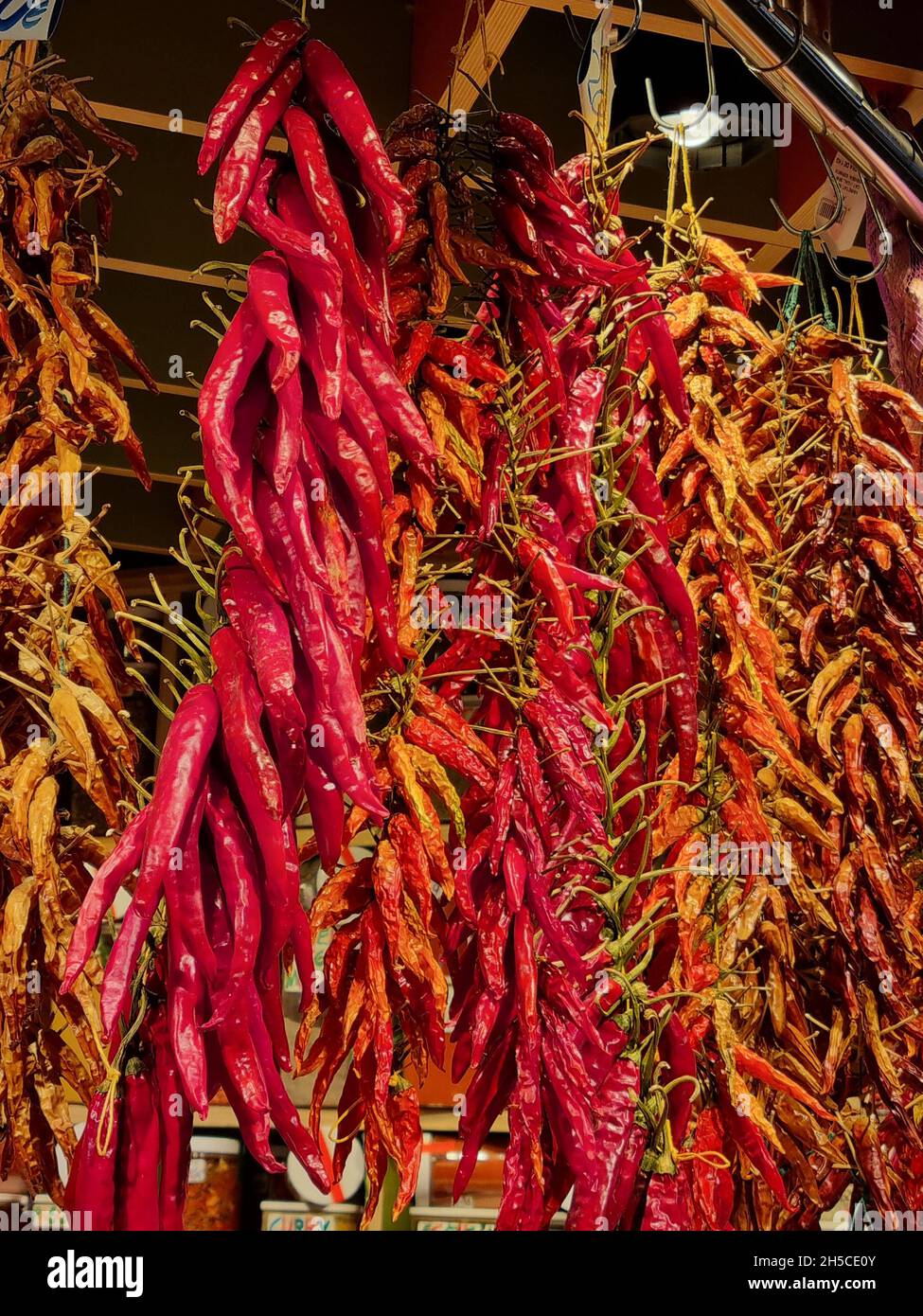 Vertical shot of colorful hot chili peppers hanging at a food market ...