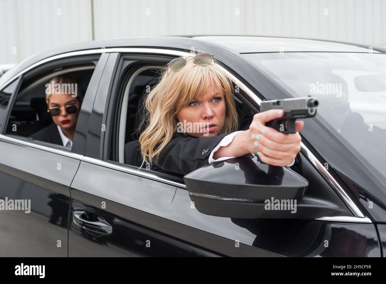 Professional armed team of female and male bodyguards shoot and protect ...