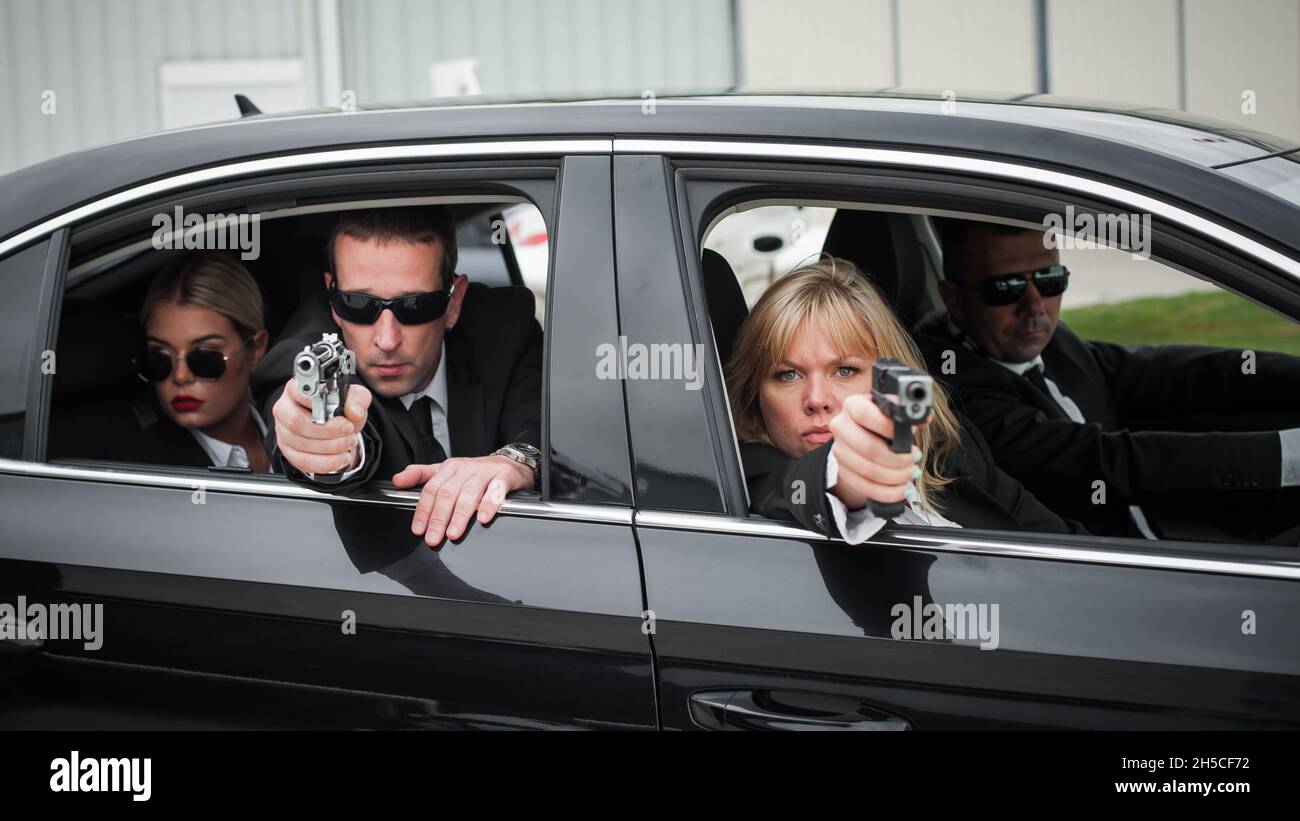 Professional armed team of female and male bodyguards shoot and protect ...
