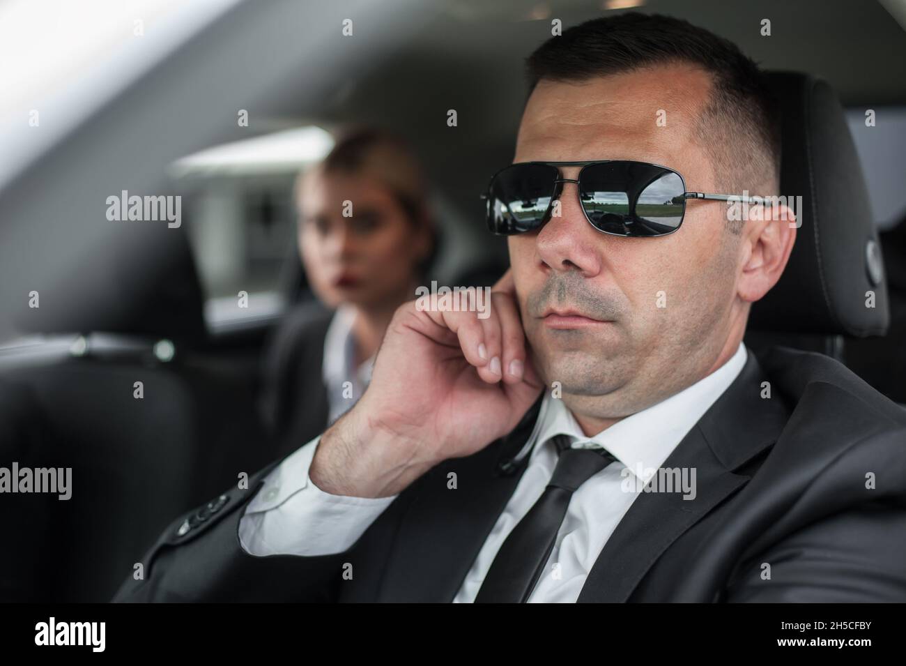 Agent in civilian black suit with handsfree earpiece radio drive ...