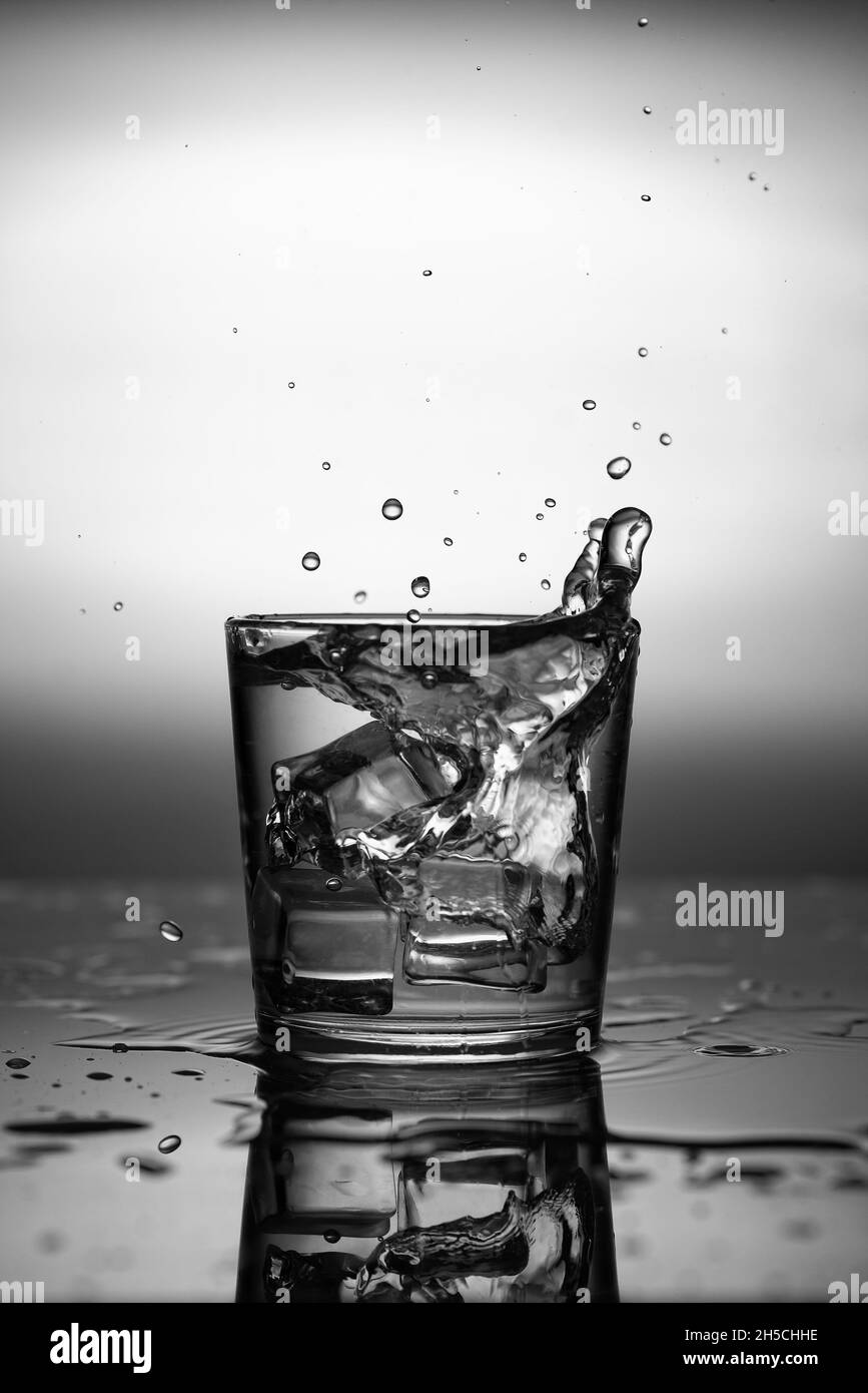 Ice cubes falling into glass of water, close up Stock Photo - Alamy