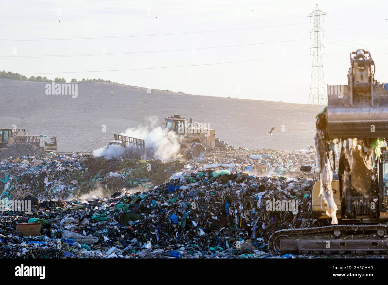 Excavator sorting metals for recycling at a recycling center, vertical ...