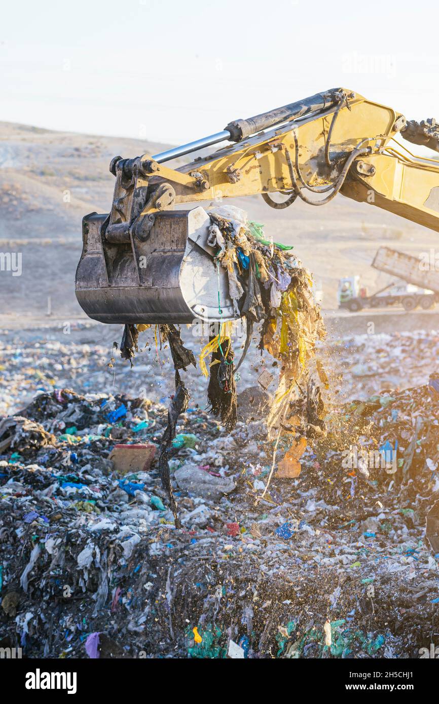 Excavator sorting metals for recycling at a recycling center, vertical ...