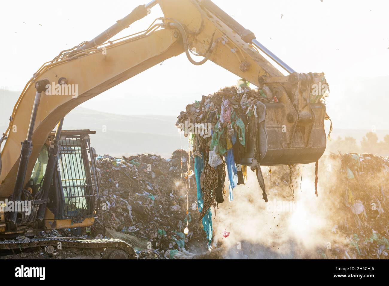 Excavator sorting metals for recycling at a recycling center, vertical ...