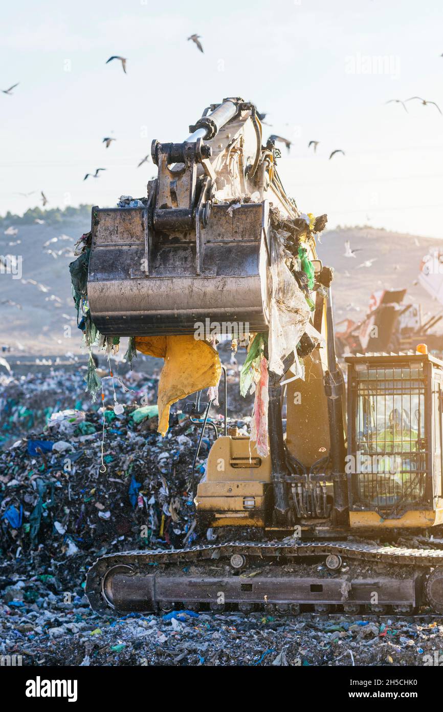Excavator sorting metals for recycling at a recycling center, vertical ...