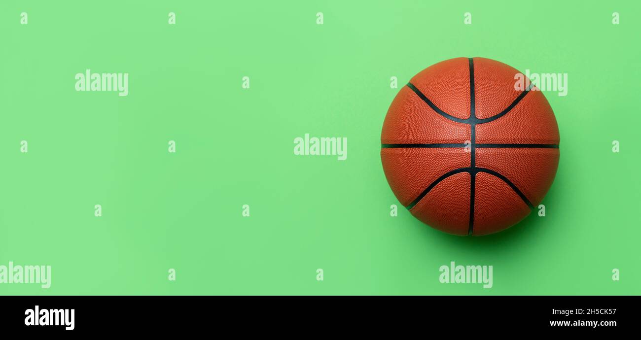 Close up of brown basketball ball isolated on green background. Sport ...