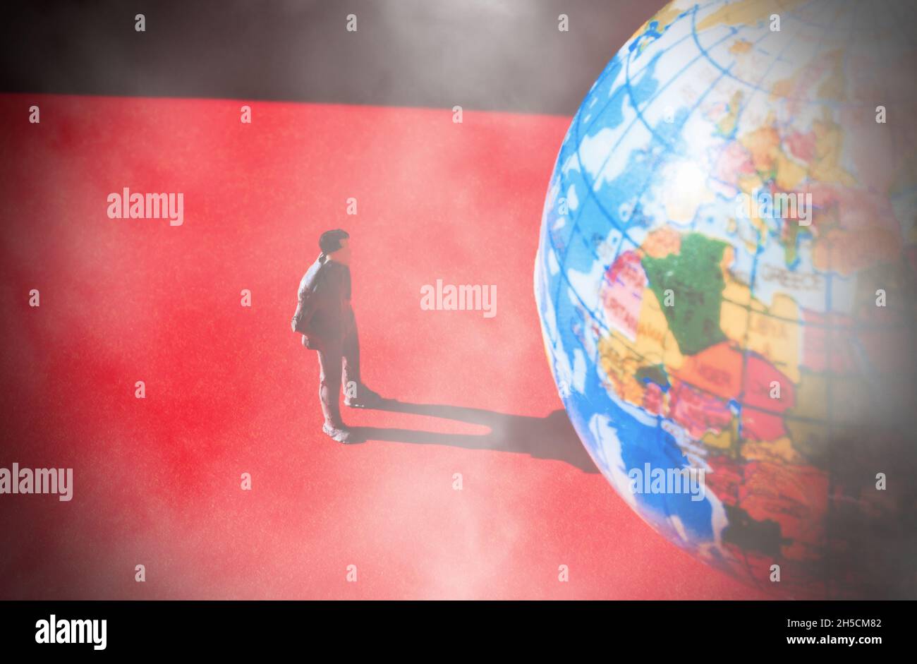 Miniature Man observing the planet earth in a red background Stock ...