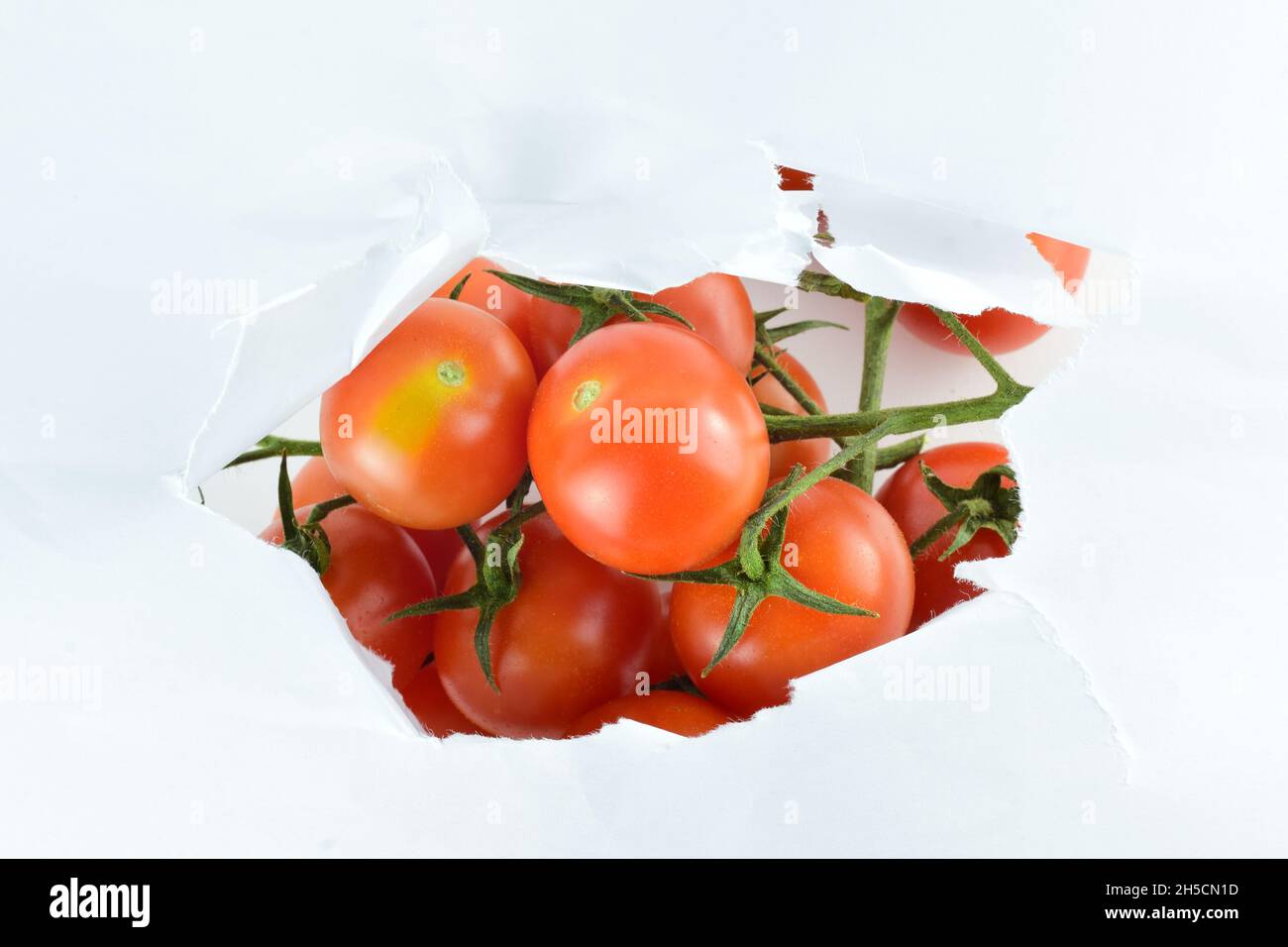 Torn paper with red tomatoes under it Stock Photo - Alamy