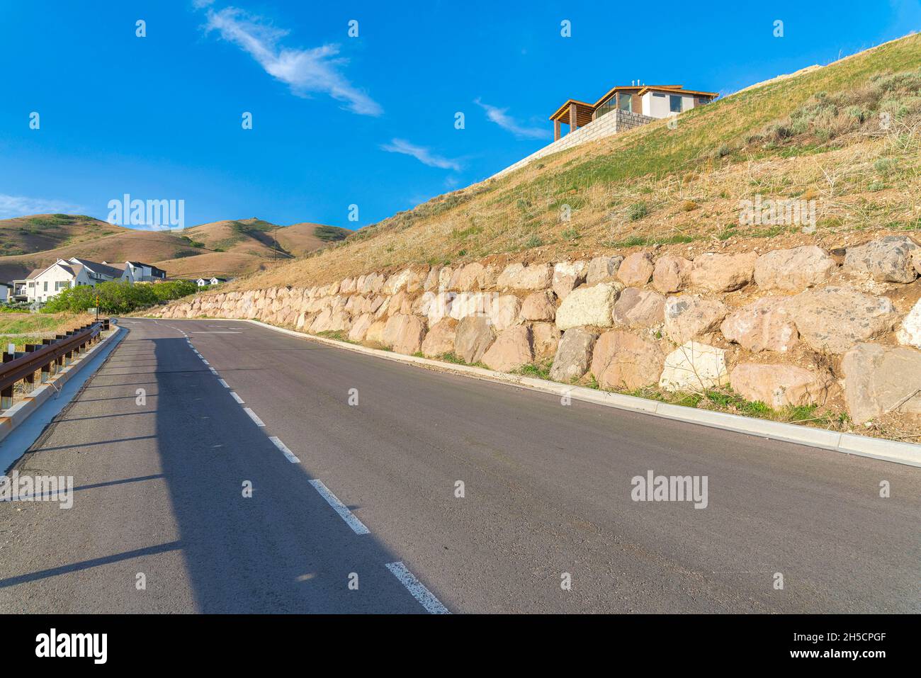 Paved road with roadside barrier beside the retaining wall of a man ...