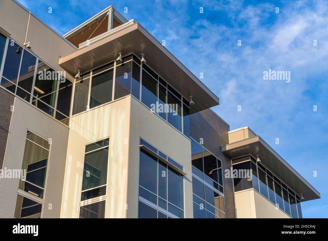 Flat building exterior in a low-angle view with glass, bricks and light ...
