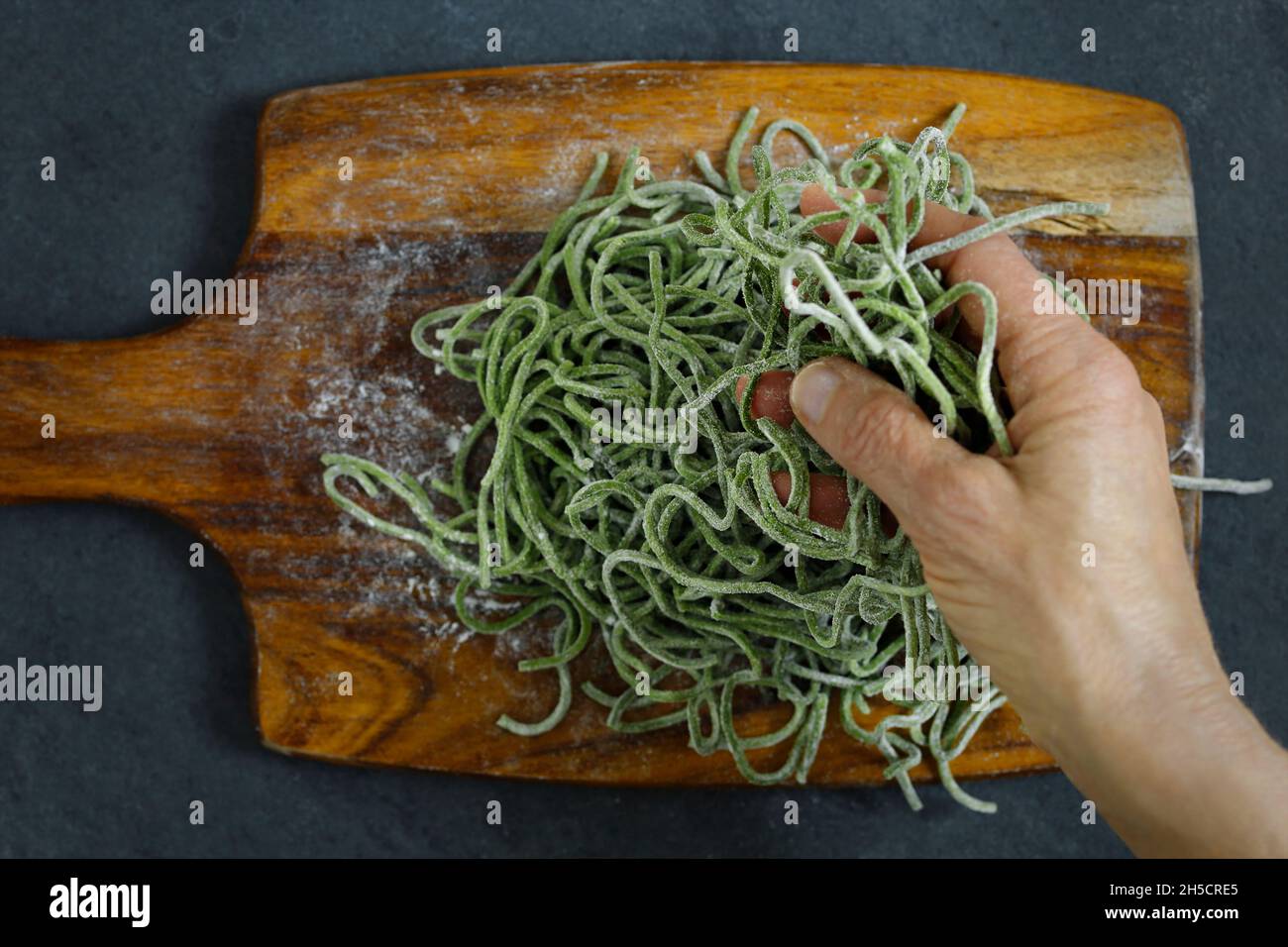 Raw spaguetti. Hand taking the pasta before cooking Stock Photo - Alamy
