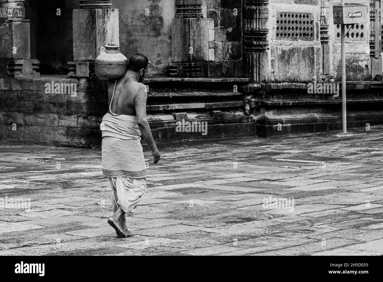 Grayscale shot of a Hindu temple priest outdoor carrying water Stock ...
