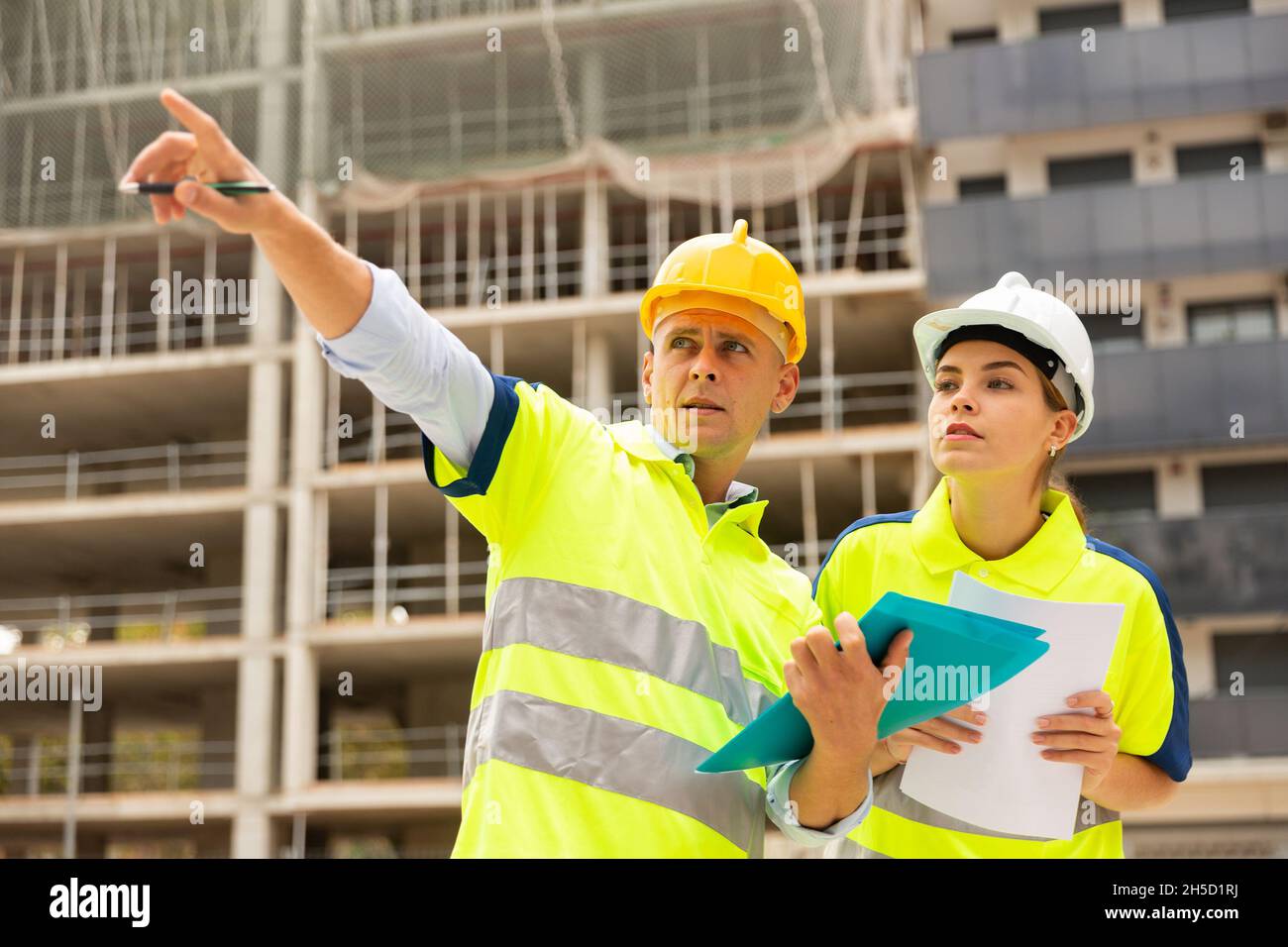 Male and female builders talking in construction site Stock Photo - Alamy