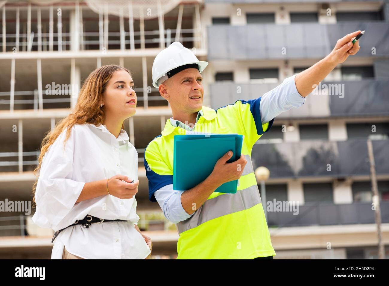Builder talking with client at construction site Stock Photo - Alamy